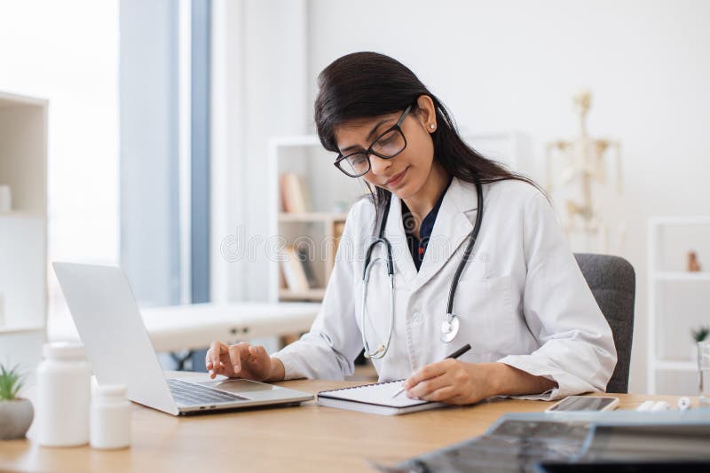 Doctor Using Computer while Sitting at Desk in Health Center Stock ...