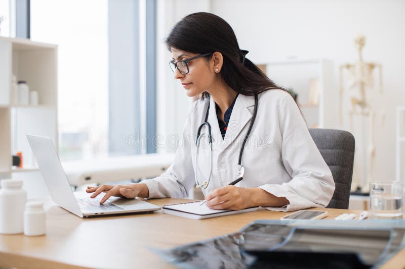 Doctor Using Computer while Sitting at Desk in Health Center Stock ...