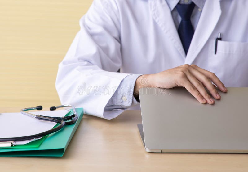 Doctor Working with Laptop Computer and Writing on Paperwork Stock ...