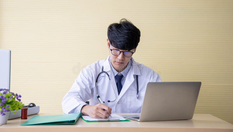 Doctor Working with Laptop Computer and Writing on Paperwork Stock ...