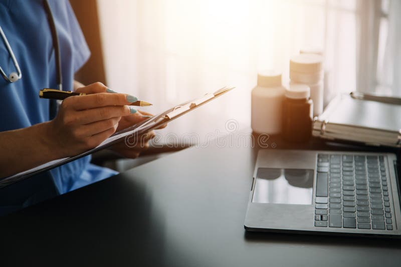Doctor Working with Laptop Computer and Writing on Paperwork. Hospital ...