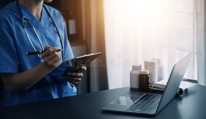 Doctor Working with Laptop Computer and Writing on Paperwork. Hospital ...