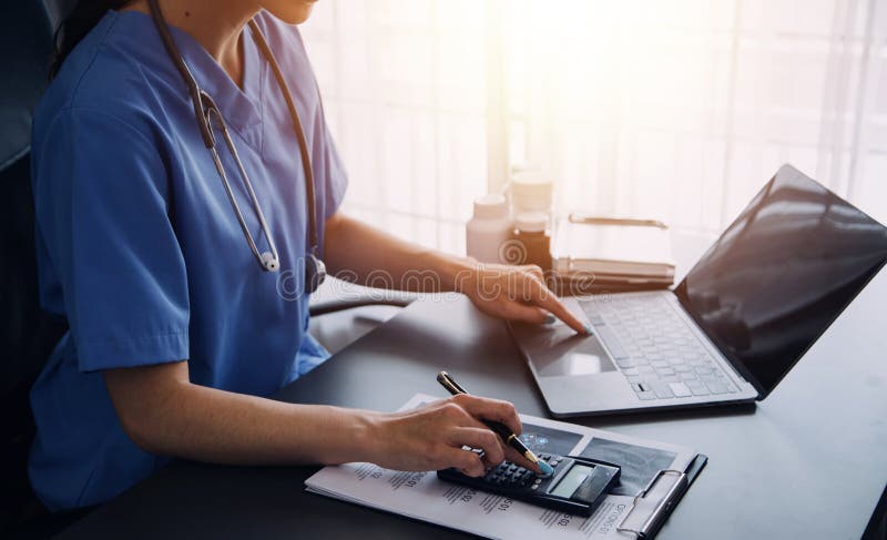 Doctor Working with Laptop Computer and Writing on Paperwork. Hospital ...