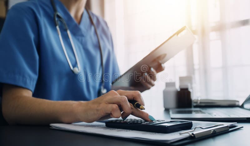 Doctor Working with Laptop Computer and Writing on Paperwork. Hospital ...