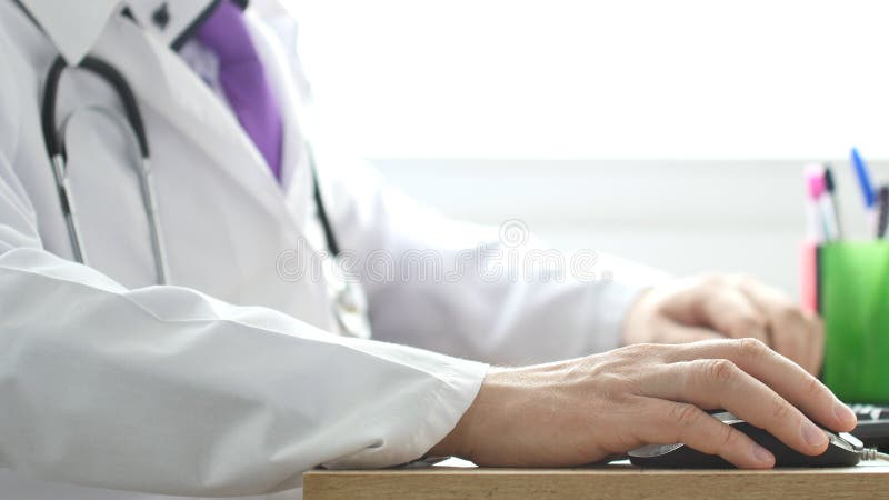 A Doctor Working on Laptop in His Cabinet and Clicking Computer Mouse ...
