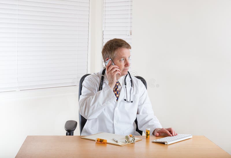 Doctor Working in Office while Communicating on Cell Phone Stock Image ...