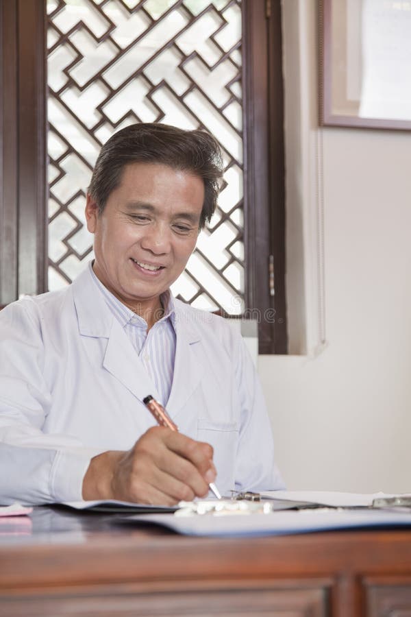 Doctor Writing on Medical Chart with a Smiling Patient Stock Image ...