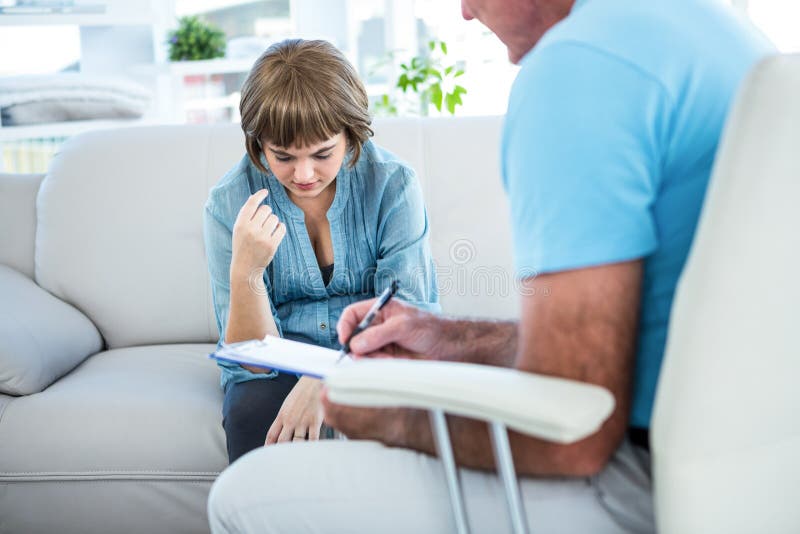 Doctor Writing on Notepad while Consulting Female Patient Stock Photo ...