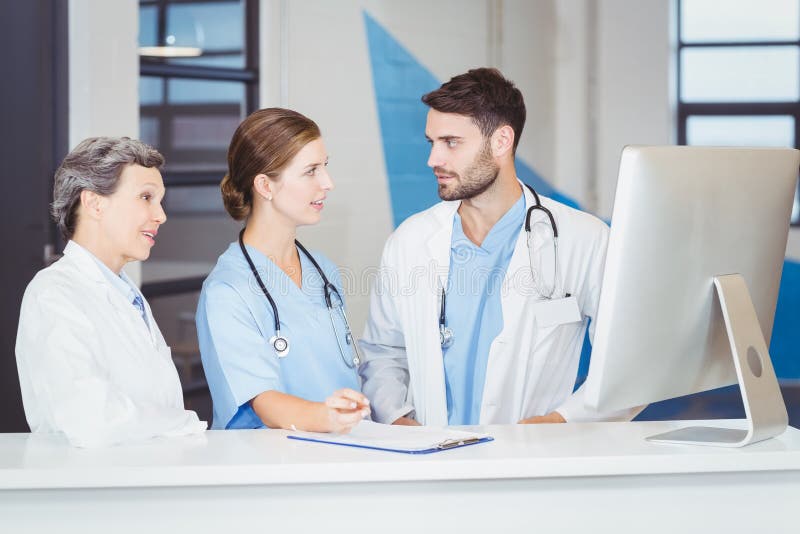 Doctors Discussing at Computer Desk Stock Photo - Image of service ...
