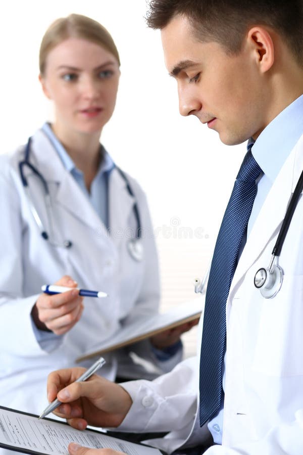 Doctors Writing Papers Using Clipboard. Physicians Discussing ...