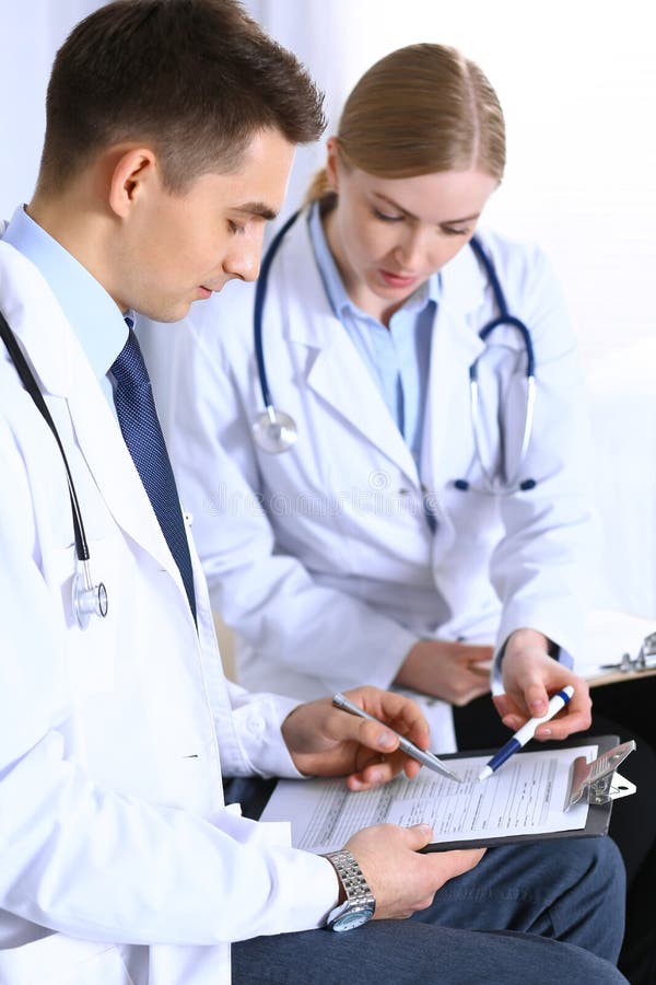 Doctors Writing Papers Using Clipboard. Physicians Discussing ...