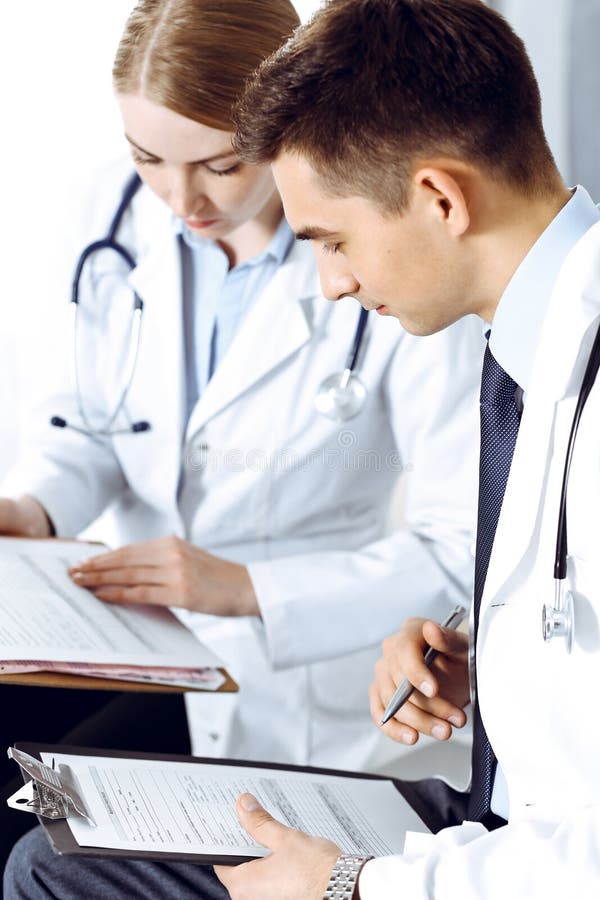 Doctors Writing Papers Using Clipboard. Physicians Discussing ...
