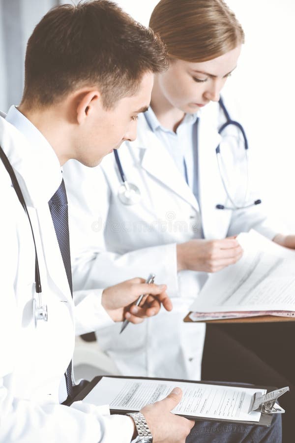 Doctors Writing Papers Using Clipboard. Physicians Discussing ...