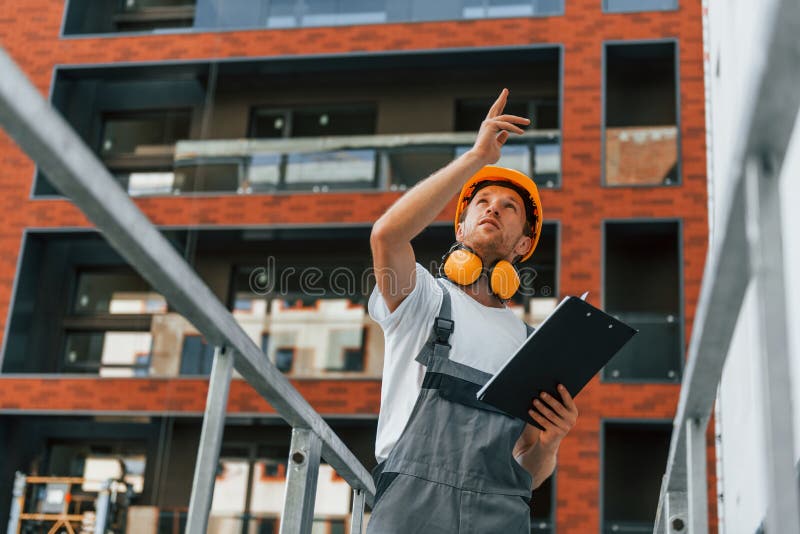 With Documents in Hands. Young Man Working in Uniform at Construction ...