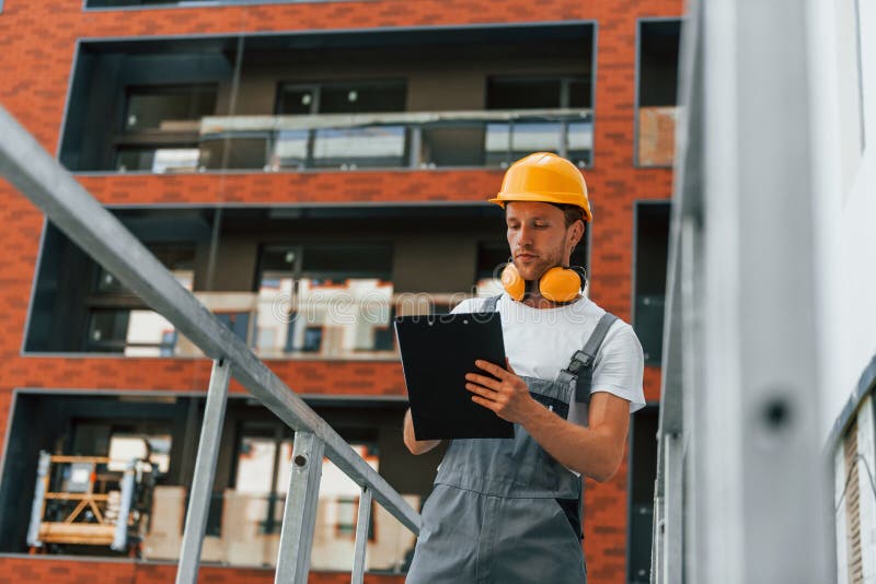 With Documents in Hands. Young Man Working in Uniform at Construction ...