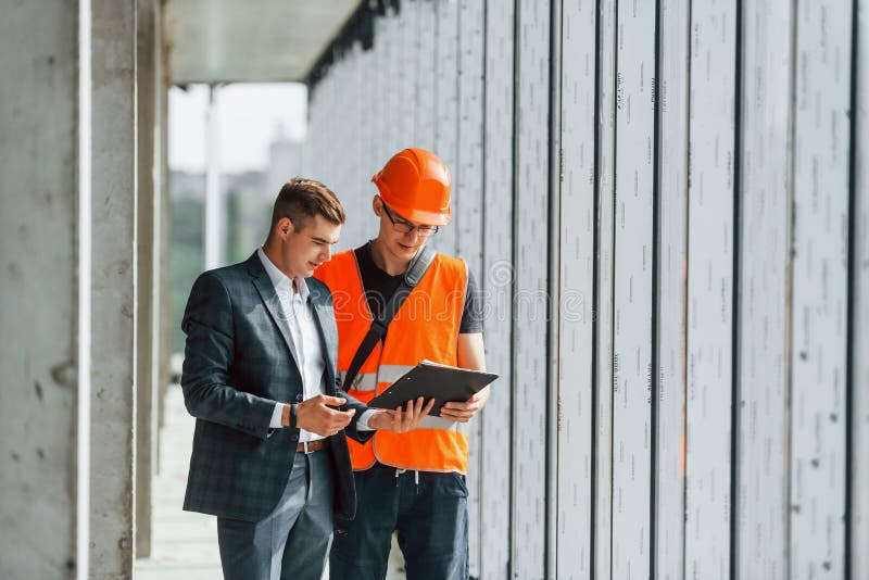 With Documents. Man in Suit and Handyman in Orange Protective Wear is ...