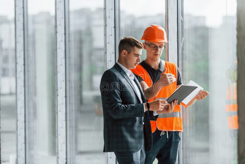 With Documents. Man in Suit and Handyman in Orange Protective Wear is ...