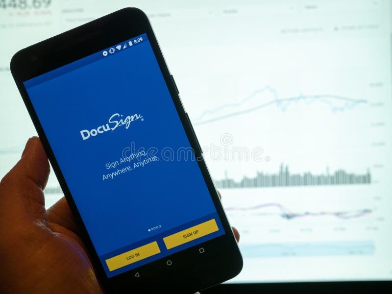 DocuSign Mobile App Held in Front of a Bright Stock Price Chart ...