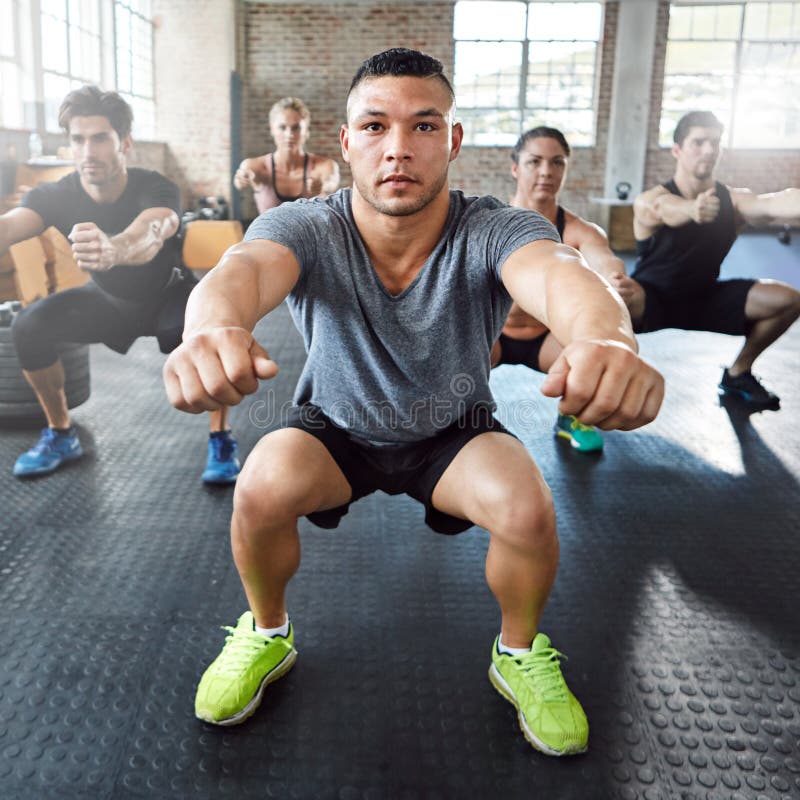 Getting Focused on Her Fitness. a Group of People Doing Squats in a Gym ...