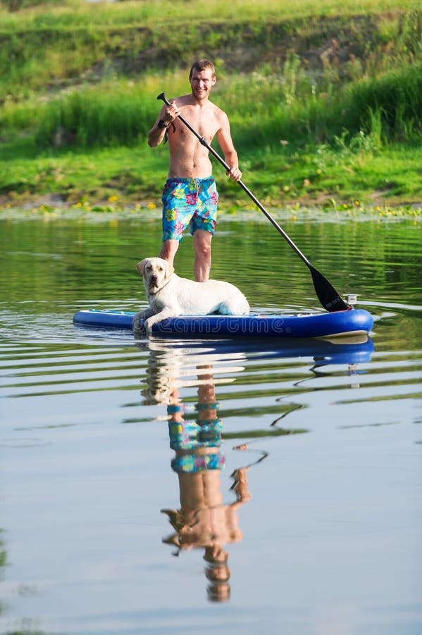 The Dog and the Man Float by the Boat on the Lake. Stock Photo - Image ...