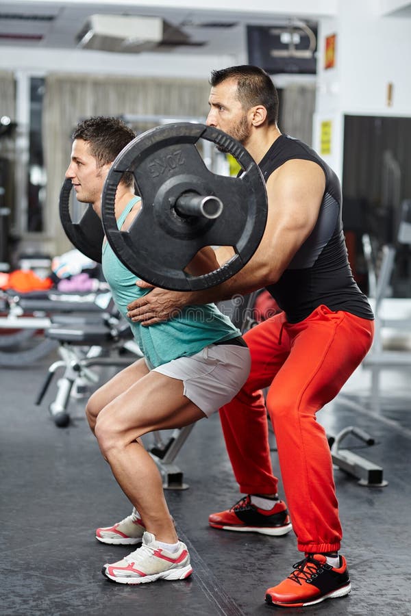 Doing Barbell Squats with Personal Instructor Stock Image - Image of ...