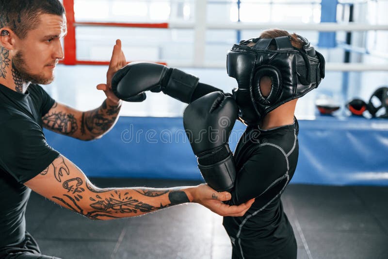 Doing Some Punches. Coach is Teaching the Boy Box Techniques Indoors ...