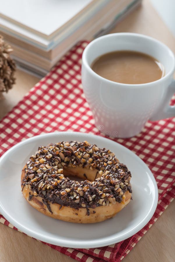 Donut Chocolate with Nut Topping and a Cup of Coffee on the Table Stock ...