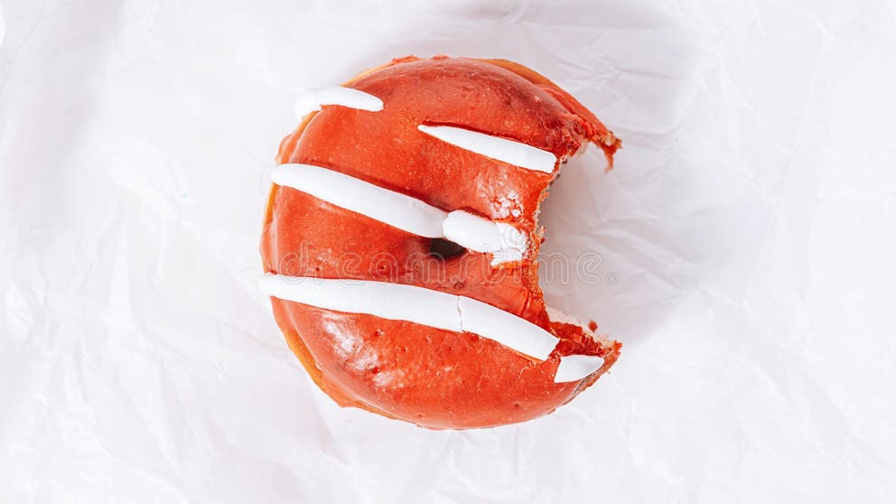 Donut with Red Icing and White Lines on White Paper with a Bite Stock ...
