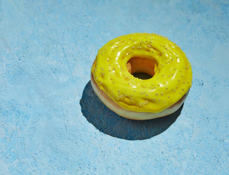 Donut with Yellow Frosting and Sprinkles on Blue Background Stock Image ...