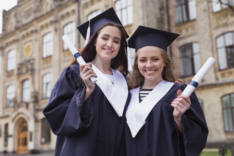 Dos Graduados Bonitos Que Llevan Birretes Imagen de archivo - Imagen de ...