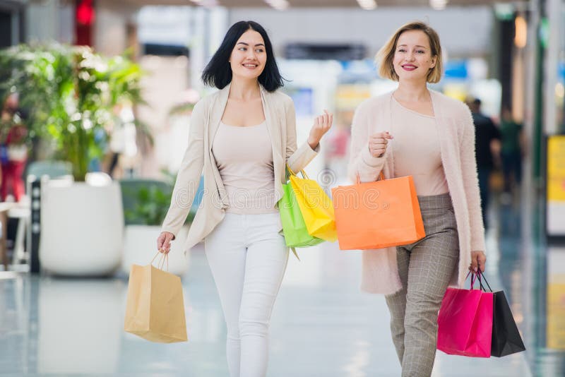 Dos Mujeres Jovenes Felices Que Caminan En Alameda De Compras Con Los ... Dos Mujeres Jovenes Felices Que Caminan En Alameda De Compras Con Los ...