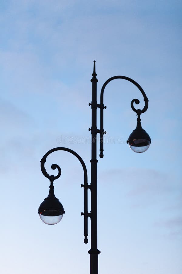 A Double Black Street Lamp with Two (2) Light Bulbs Against Cloudy Blue ...