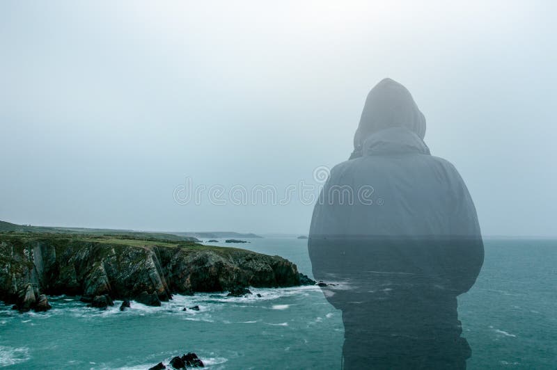 A Double Exposure of a Hooded Figure Looking Out at a Moody Rugged ... A Double Exposure of a Hooded Figure Looking Out at a Moody Rugged ...