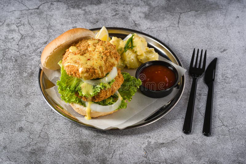 Double Fish Burger with Potato Salad on a Metal Plate Stock Photo ...