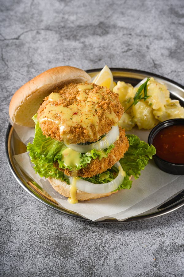 Double Fish Burger with Potato Salad on a Metal Plate Stock Photo ...