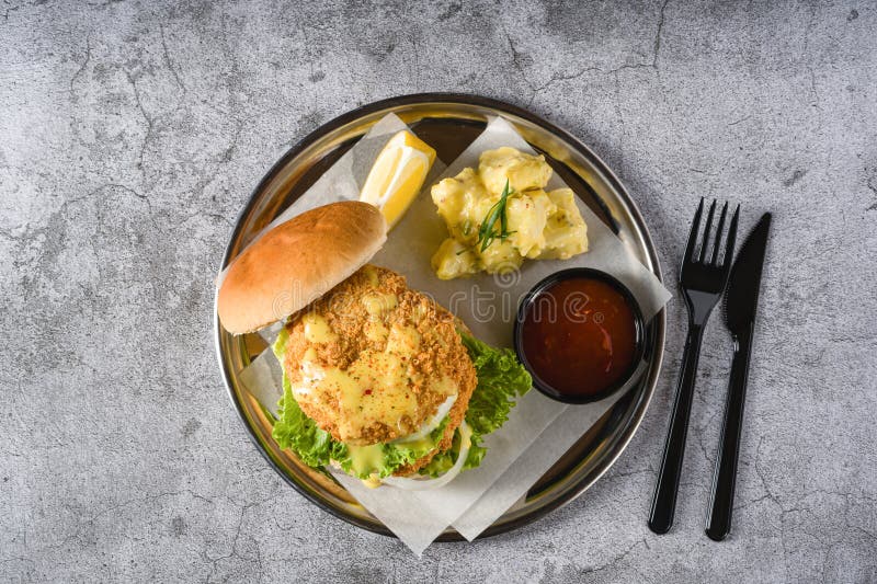 Double Fish Burger with Potato Salad on a Metal Plate Stock Photo ...