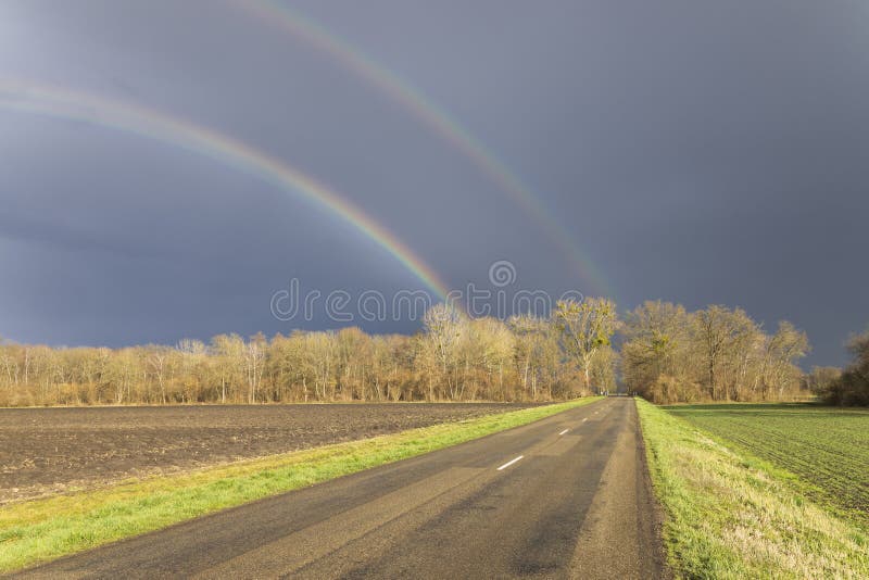 Double Rainbow Appearing Over Empty Asphalt Road and Cultivated Fields ...