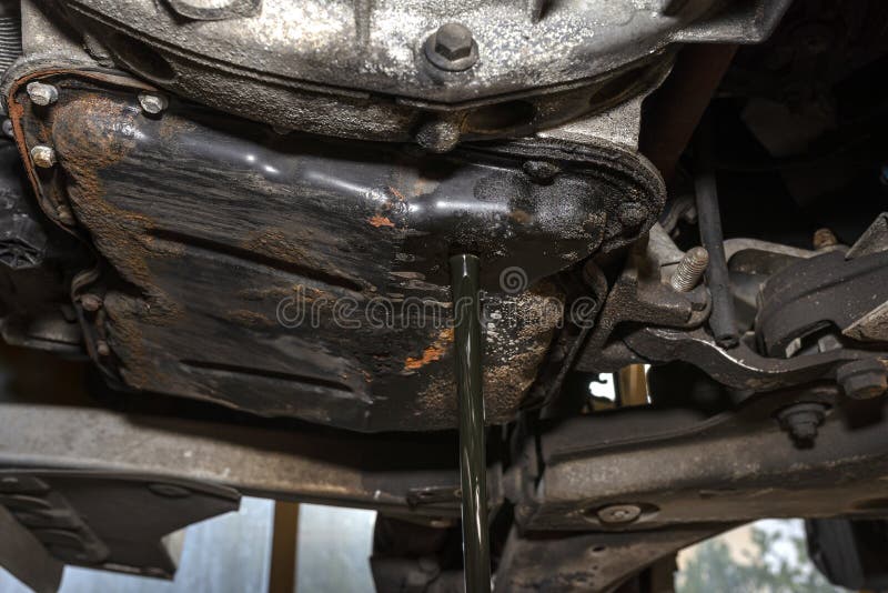 Draining Used Diesel Engine Oil from an Oil Pan into a Metal Container ...