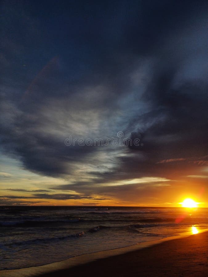 Dramatic Beach Sunset with Cloudy Sky. Golden Light Reflects on the ...
