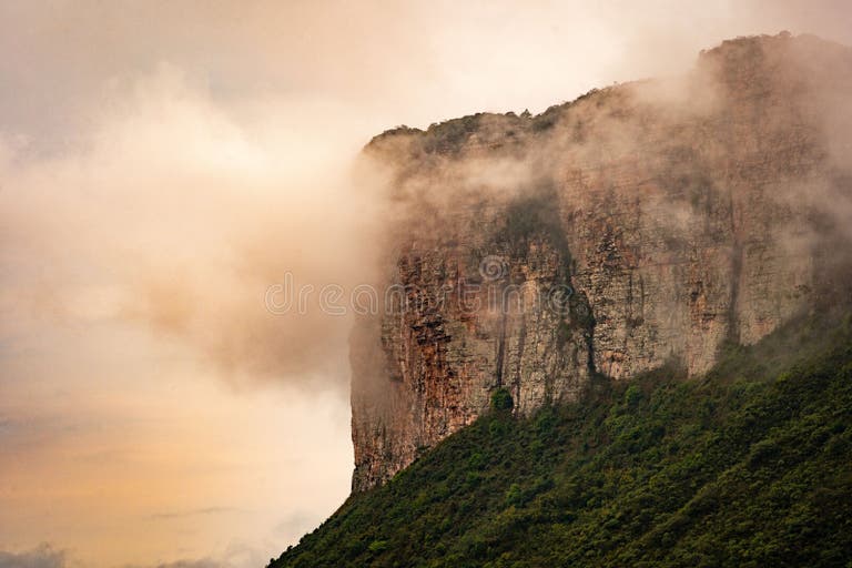 Dramatic Cliff Face Enveloped in Mist Under a Soft Orange Sky. Stock ...