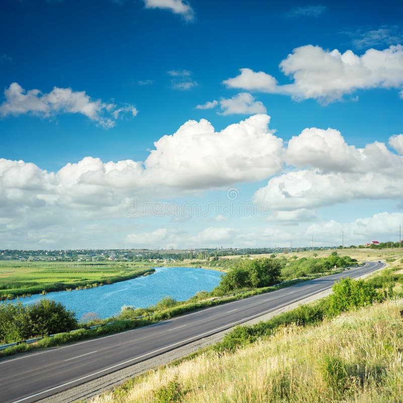 Dramatic Clouds Over River and Asphalt Road Stock Image - Image of tree ...