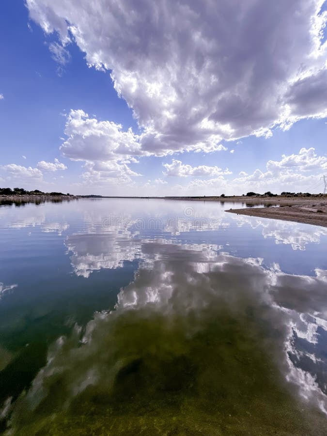 Dramatic Clouds Reflecting on Calm Lake Surface Under Vibrant Sky Stock ...