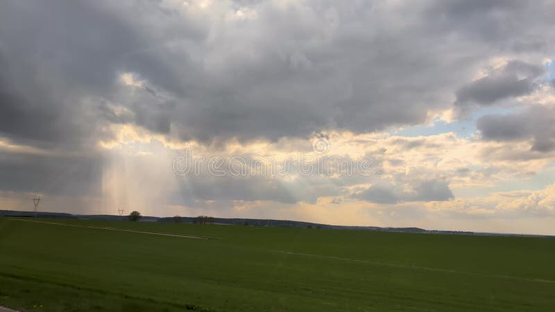 Dramatic Cloudy Sky with Sun Rays Breaking through Over a Green Field ...