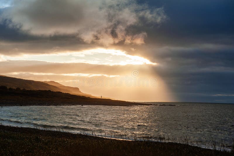Dramatic Coastal Sunset with Sun Rays through Dark Clouds, Casting ...