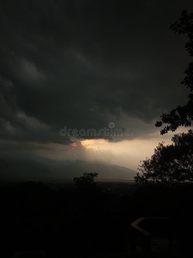 A Dramatic Landscape Captures the Golden Sunrays Piercing through Heavy ...