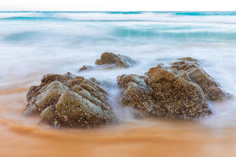 Dramatic Moving Wave Around Big Rocks on Clear Water Beach Stock Image ...