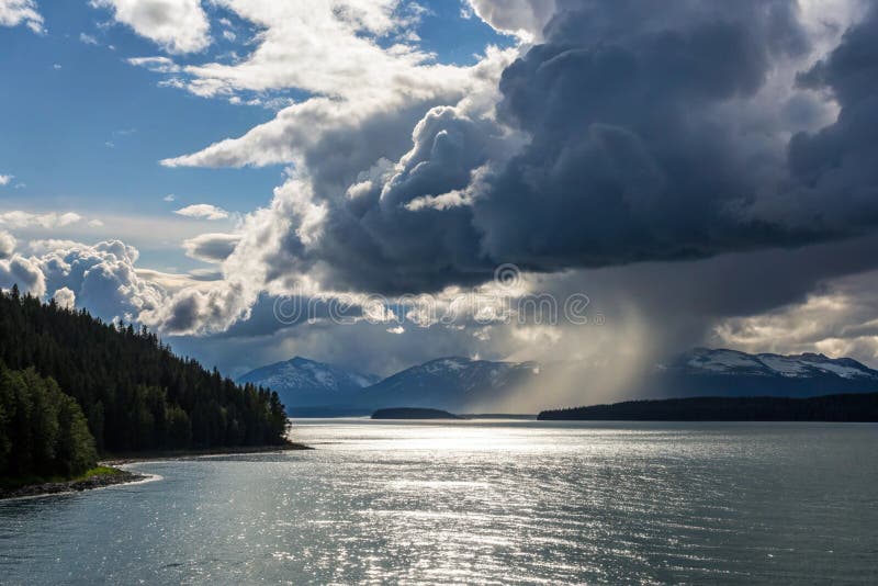 Beautiful Clouds Formations Hover Over Tranquil Water with Sunlight Reflections and a Storm in ...
