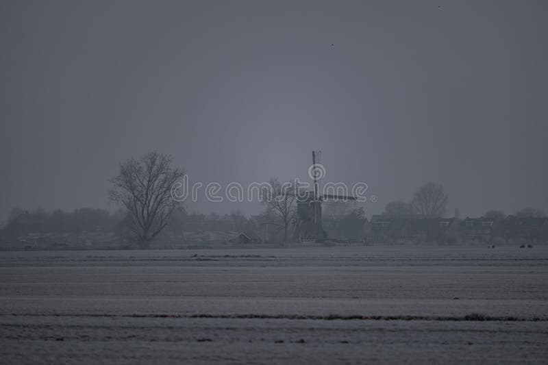 The Dramatic Scene with a Dutch Windmill in a Foggy and Cold Winter ...