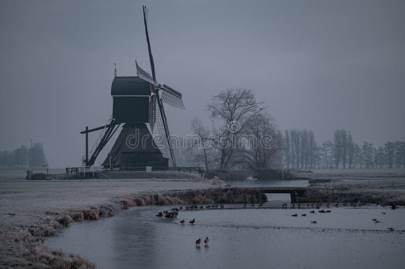 The Dramatic Scene with a Dutch Windmill in a Foggy and Cold Winter ...