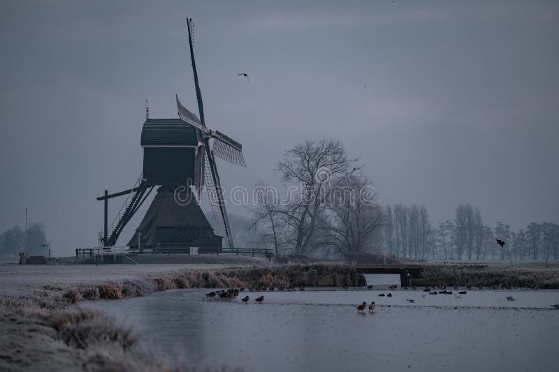 The Dramatic Scene with a Dutch Windmill in a Foggy and Cold Winter ...